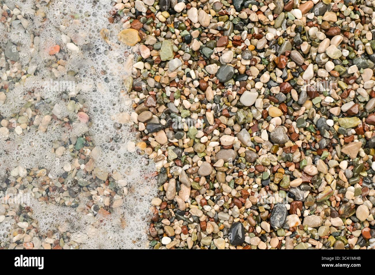 Shoreline detail with sea foam lapping at fine stones and sand. image ...