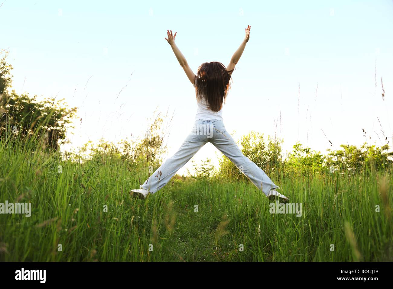 Feeling freedom. Woman jumping in nature, back view Stock Photo - Alamy
