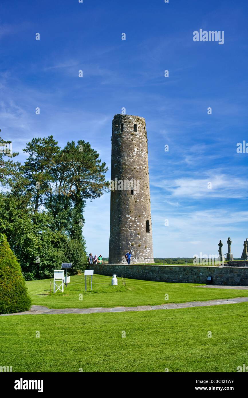 An ancient round tower stands proudly under a bright blue sky, with ...
