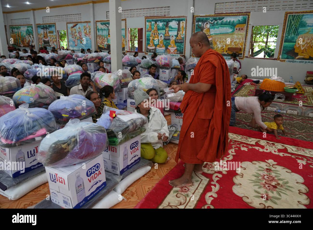 A Cambodian Buddhist monk greets villagers who wait to receive supplies ...