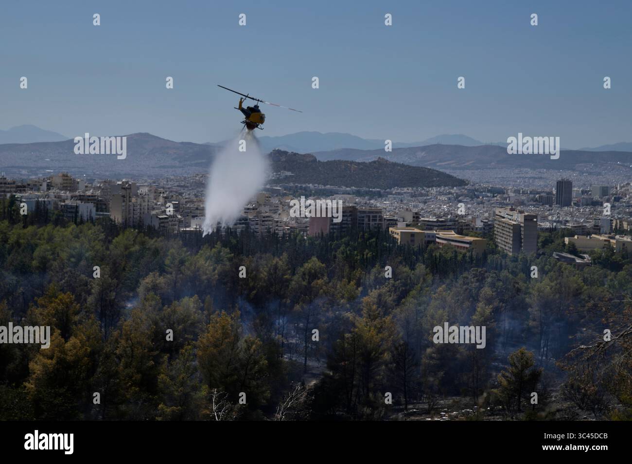 A firefighting helicopter drops water to extinguish a fire at the ...
