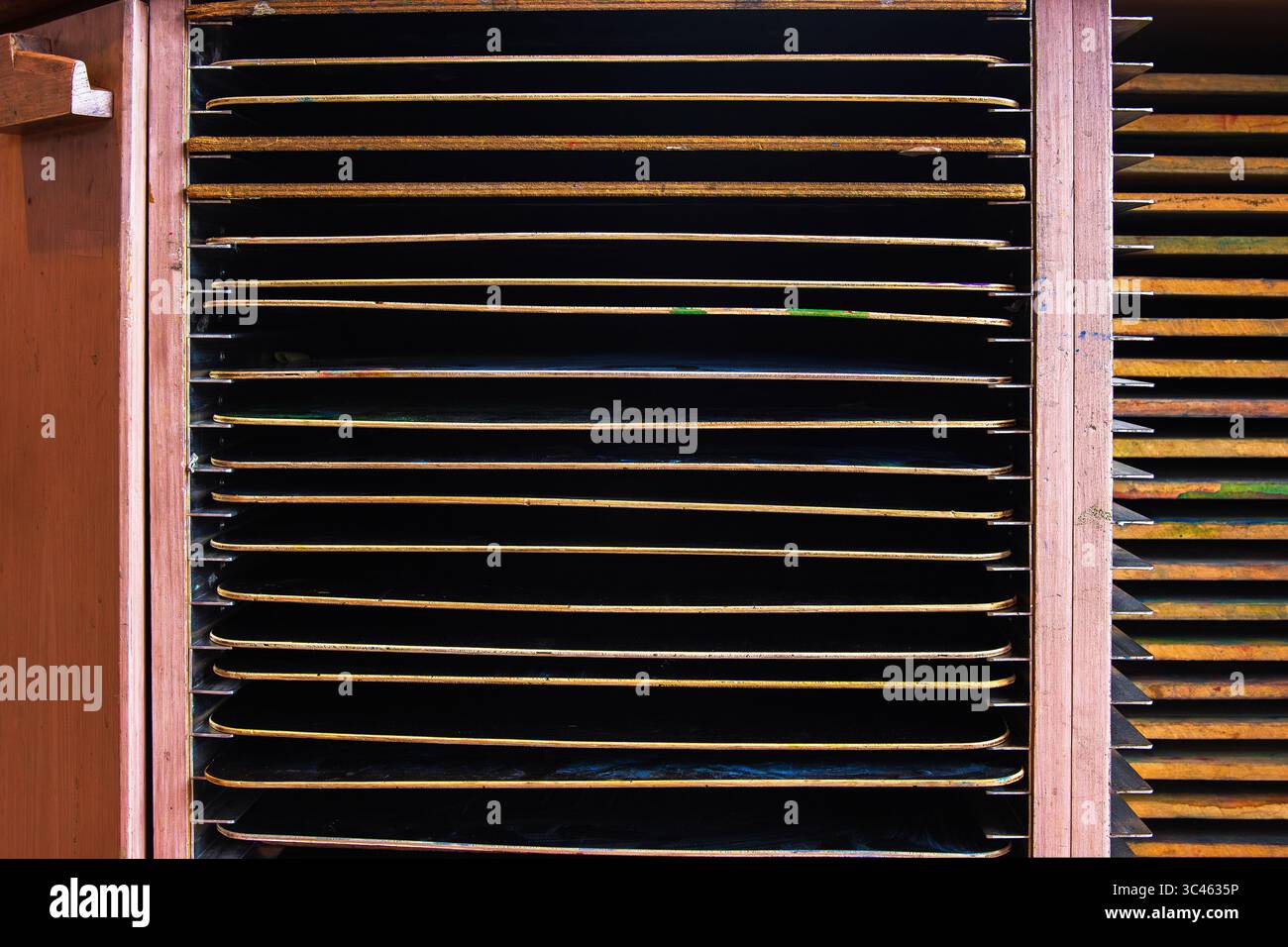 A closeup of wooden drying racks filled with stacked artwork and ...