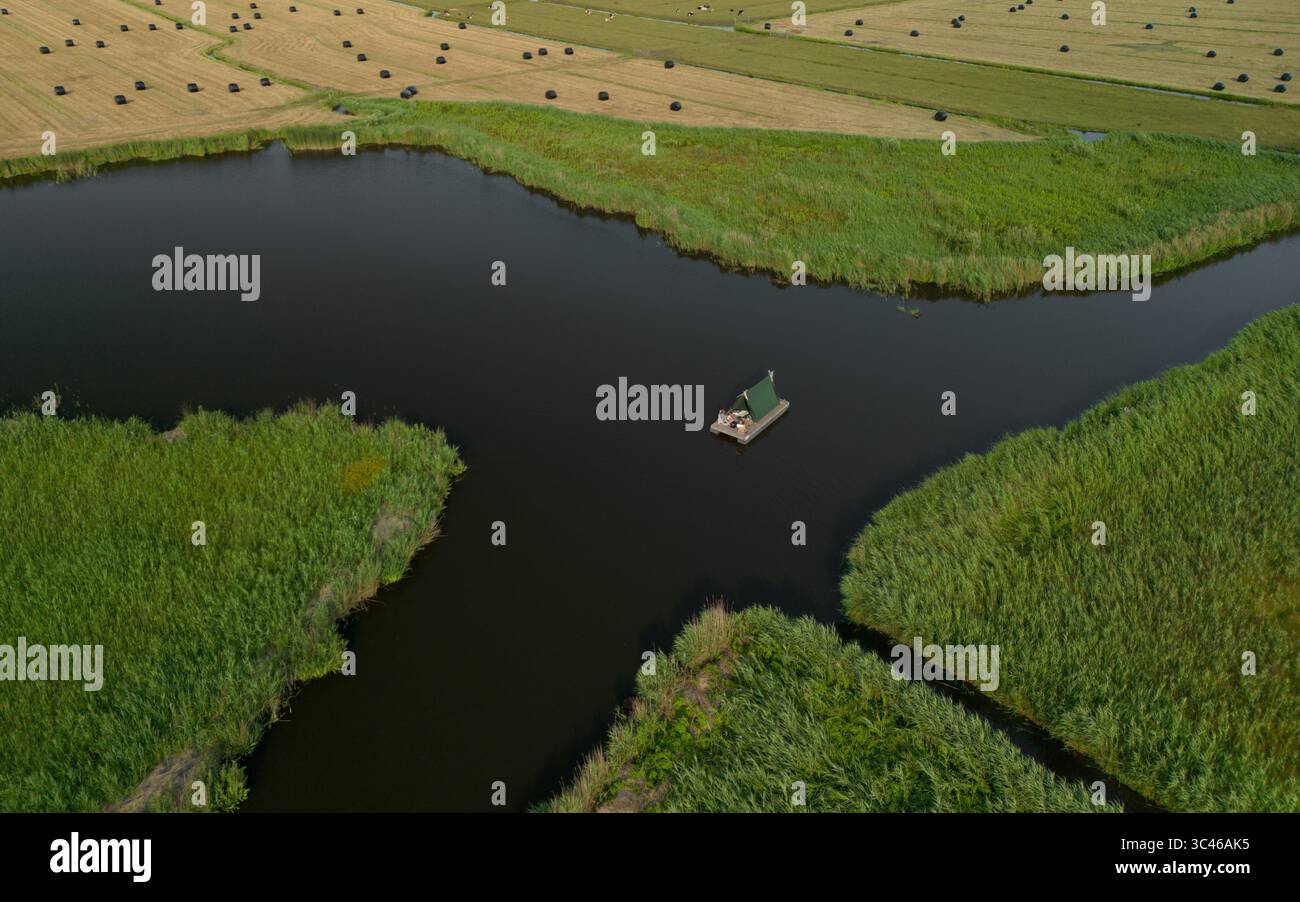 Aerial view of a solitary raft house amidst the dark waters, flanked by ...