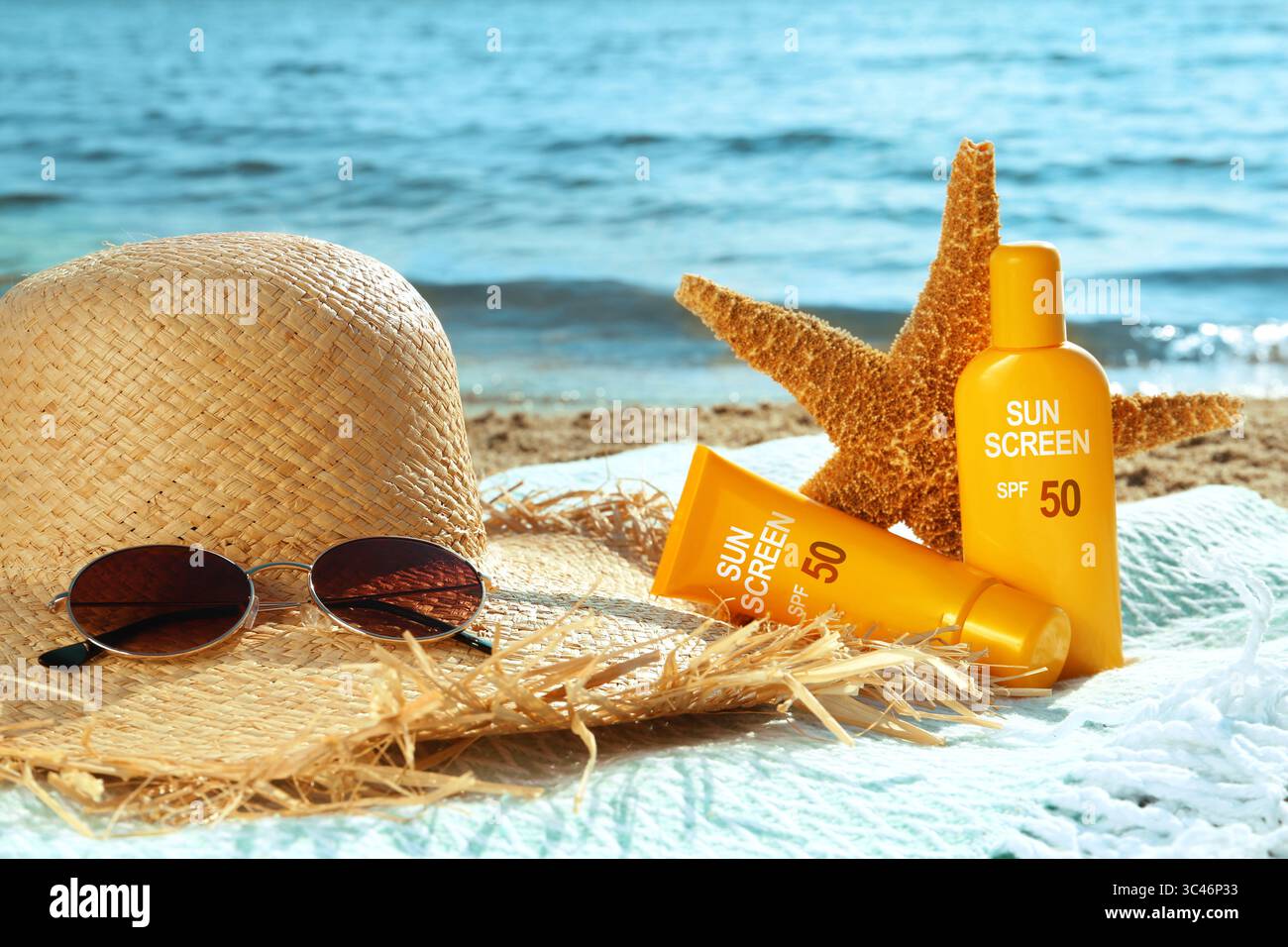 Sun protection. Sunscreens in tube and bottle, hat, sunglasses on beach ...