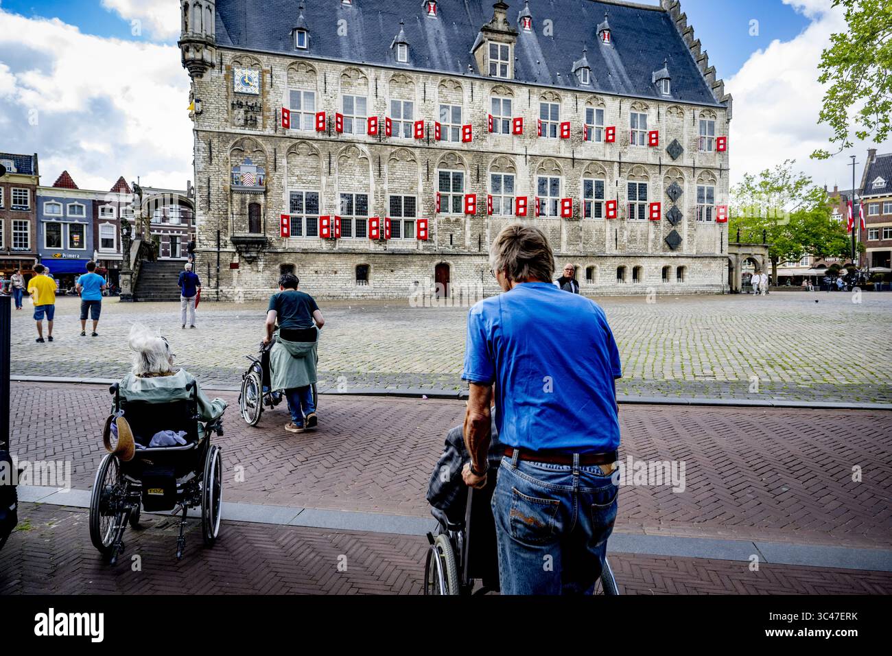 GOUDA - Walking down the street with an elderly person in a wheelchair ...