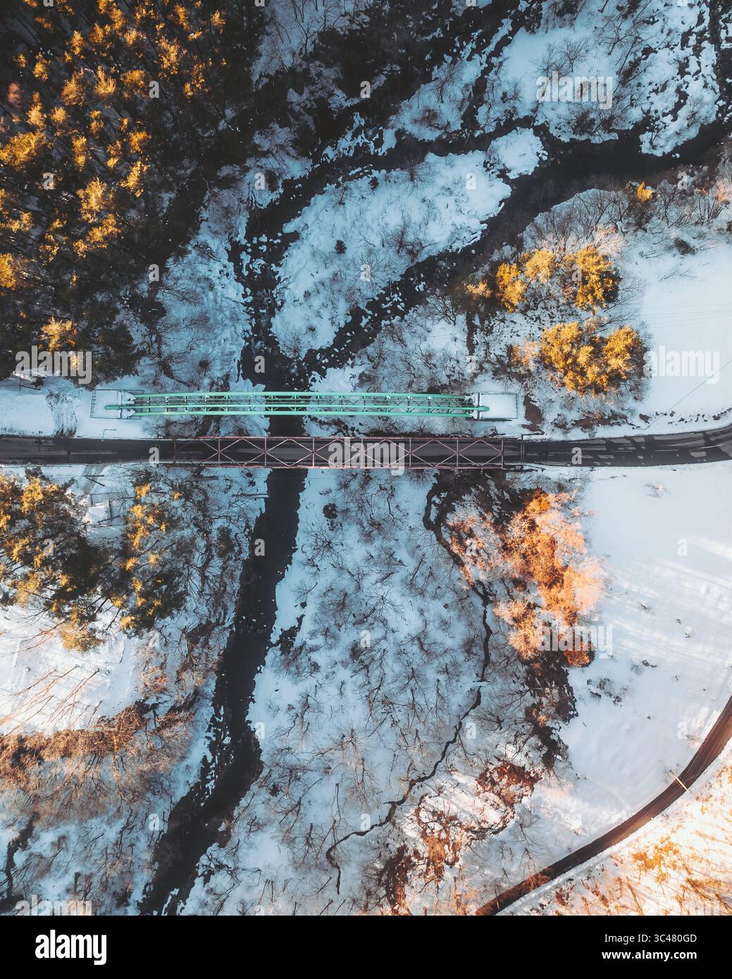 Aerial view of a crisp bridge spanning the snow-dusted river amidst the ...