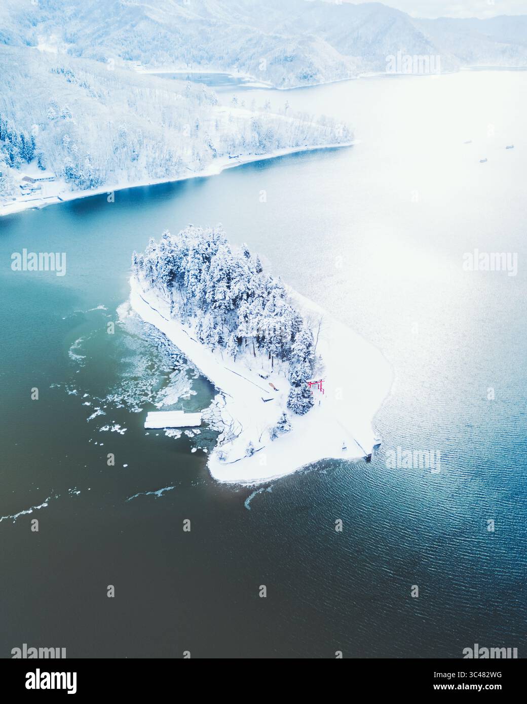 Aerial view of a snow-covered island with a small red structure ...