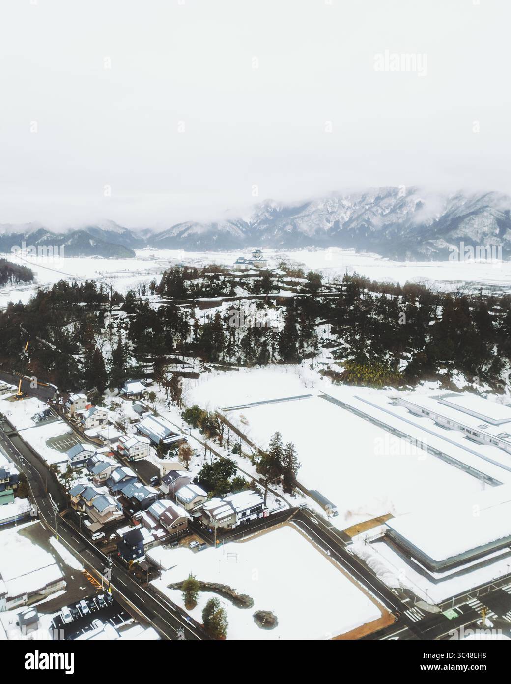 Aerial view of a snow-laden Echizen Ono Castle emerges, a stark ...