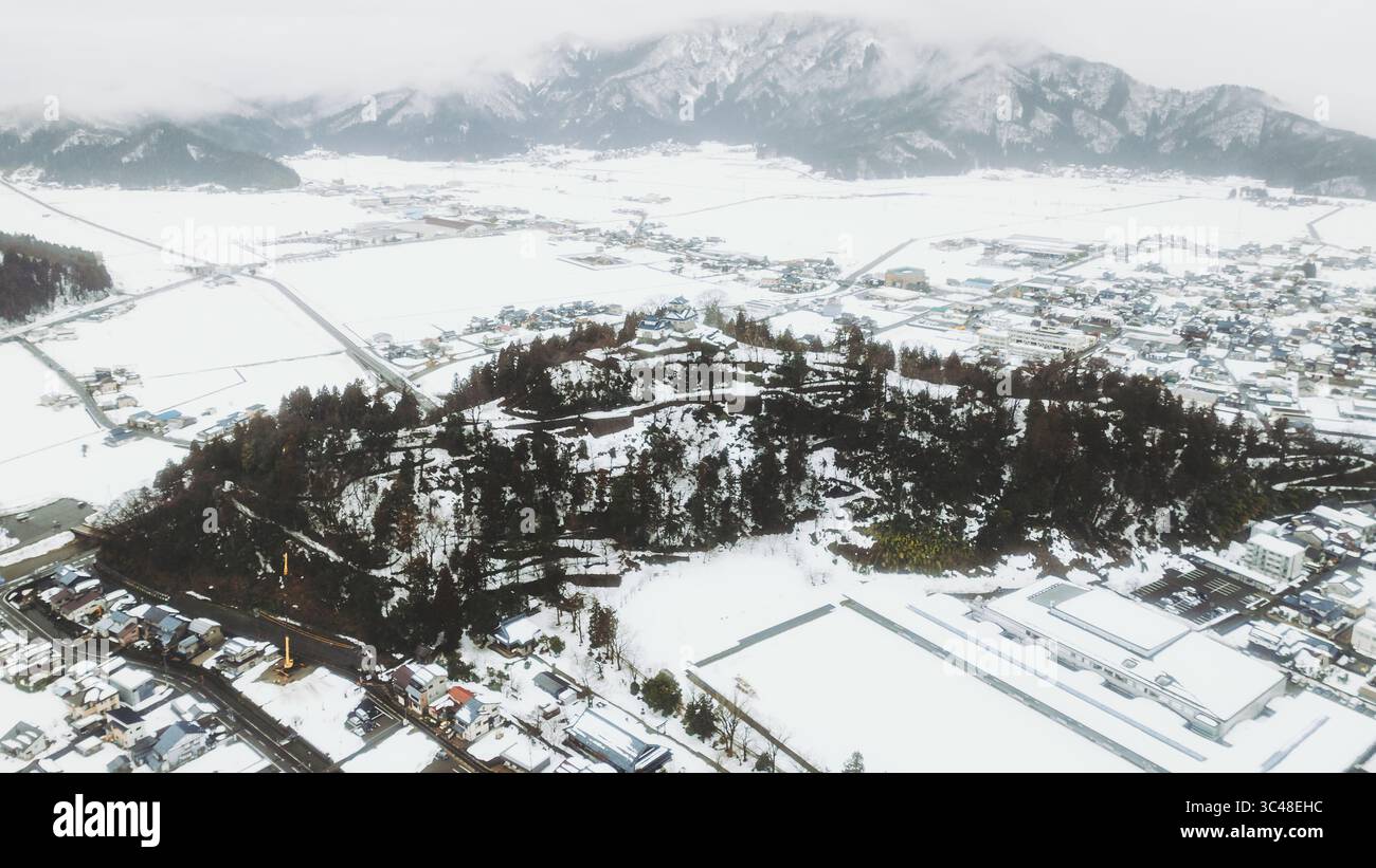 Aerial view of a snow-blanketed Echizen Ono Castle perched atop a hill ...