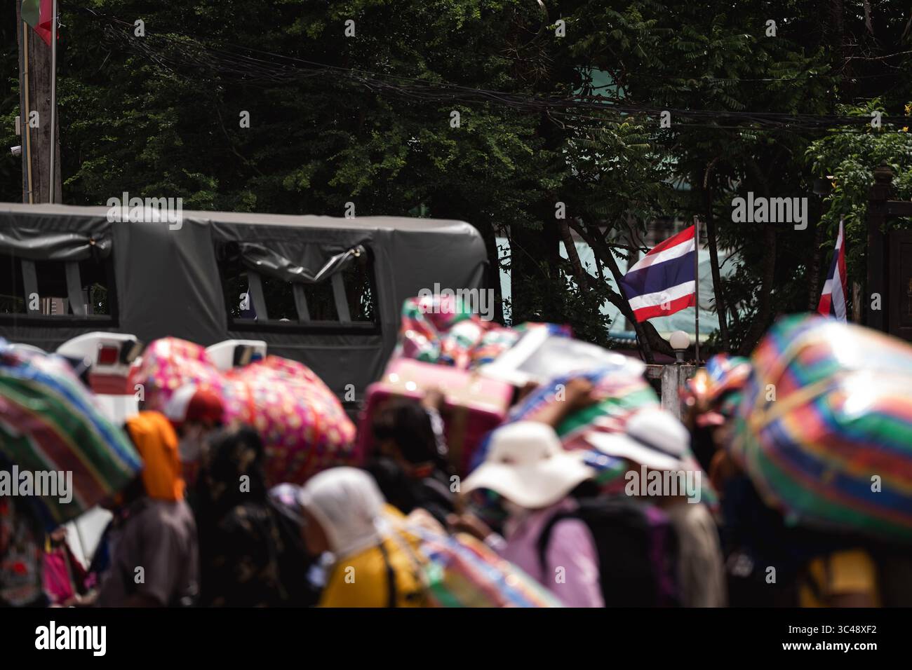 Cambodians walk past Thai military vehicles and fluttering national ...