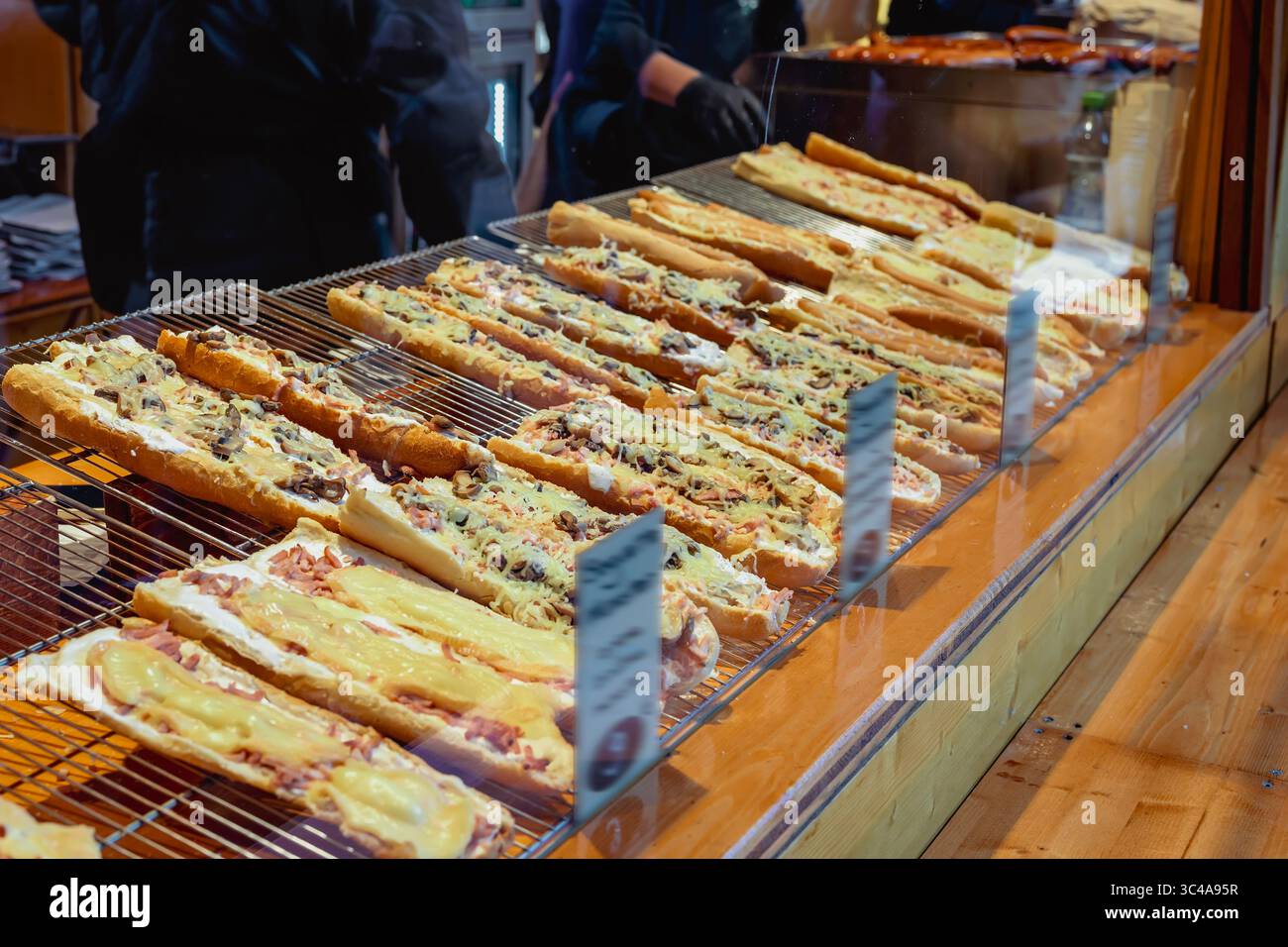 Pizza display case. Baked baguette pizzas topped with melted cheese and ...