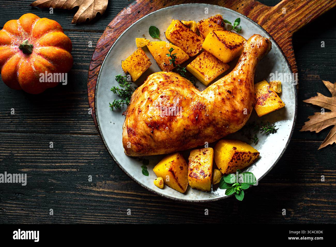 Autumn meal: roasted chicken quarter and pumpkin with garlic and herbs ...