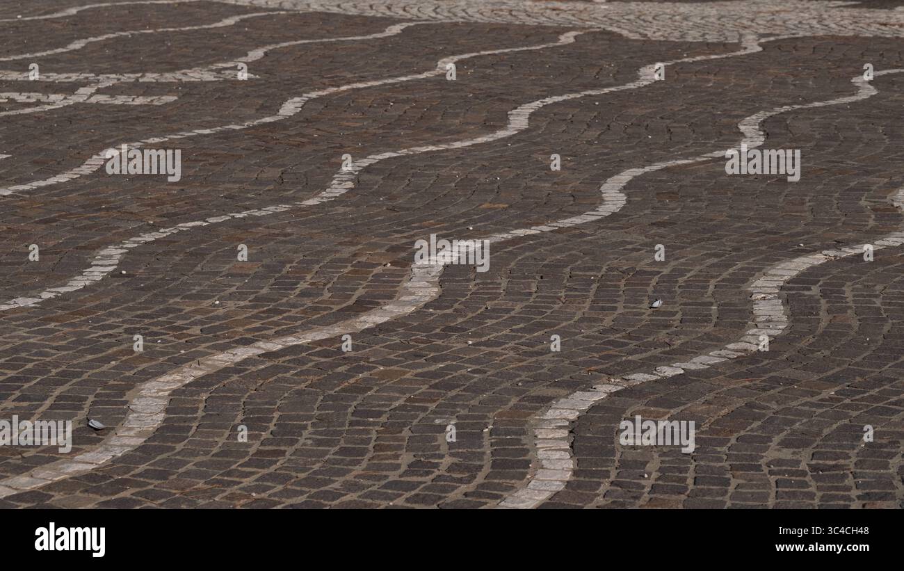 Wavy white line pattern on dark stone pavement Stock Photo - Alamy