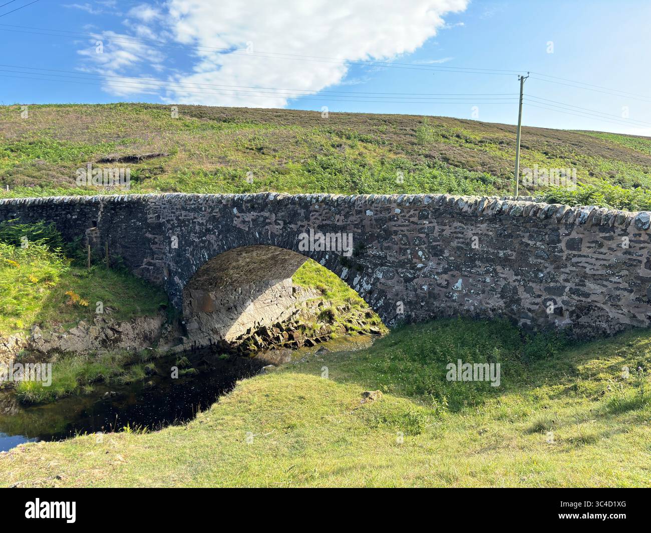 A historic single‑span stone arch bridge over the Dye Water, its ...