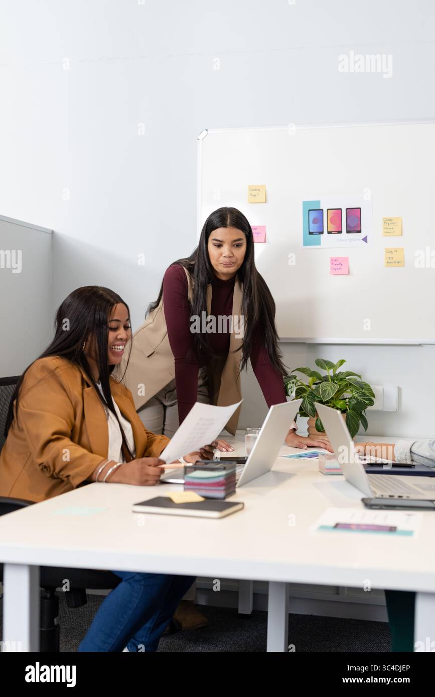 Diverse female coworkers reviewing documents in office meeting using ...