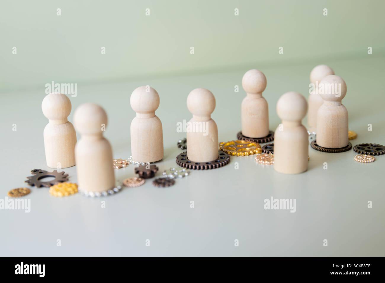 A conceptual image with wooden figures standing on interconnected gears ...