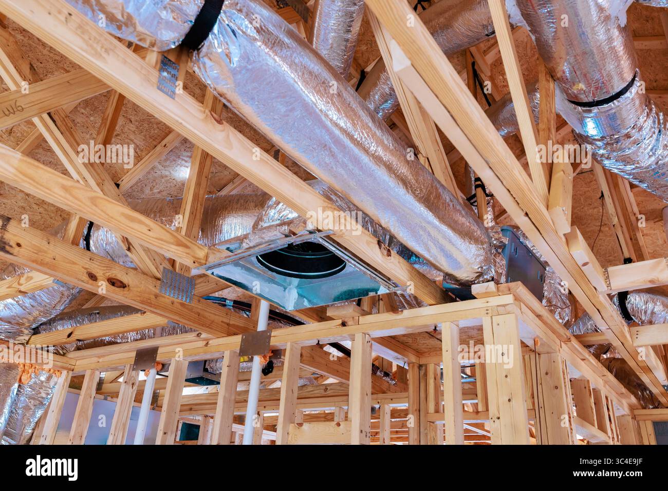 Construction workers install ductwork framing for residential ceiling ...