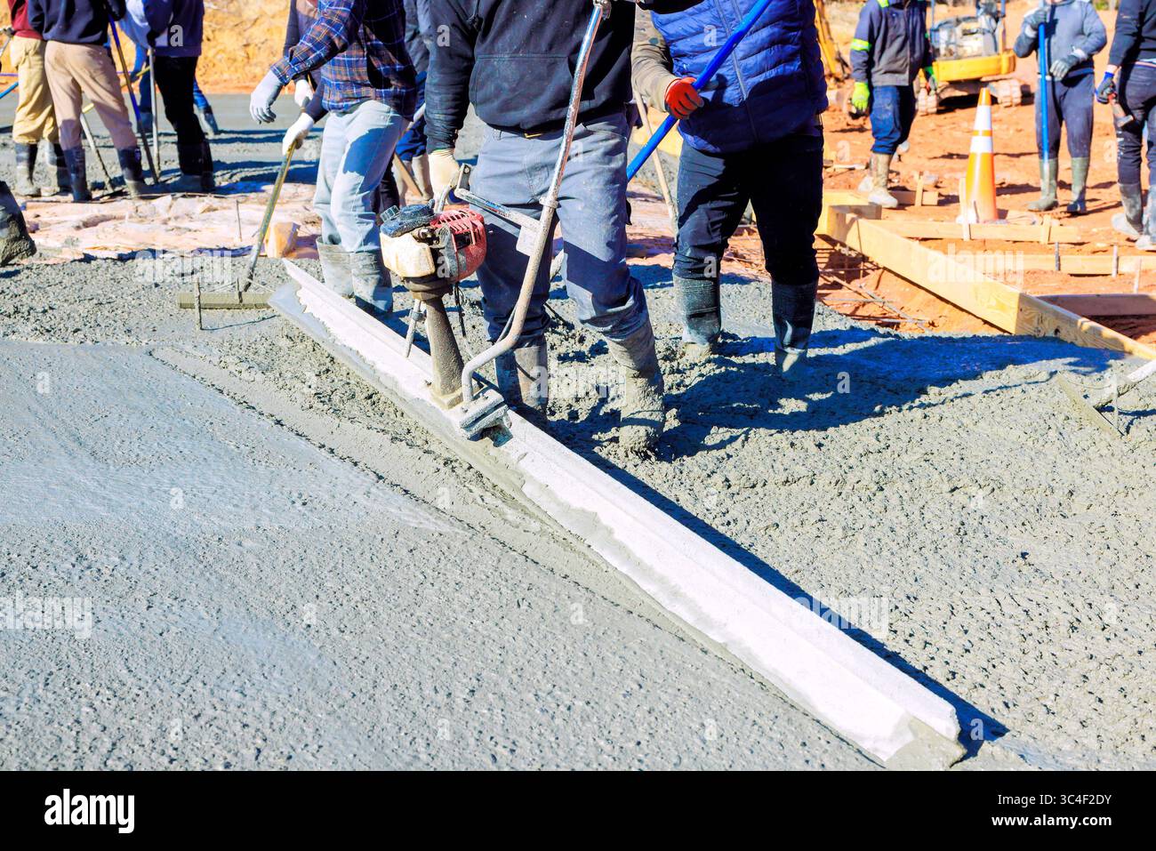 Workers skillfully apply level fresh concrete slab on site, teamwork ...