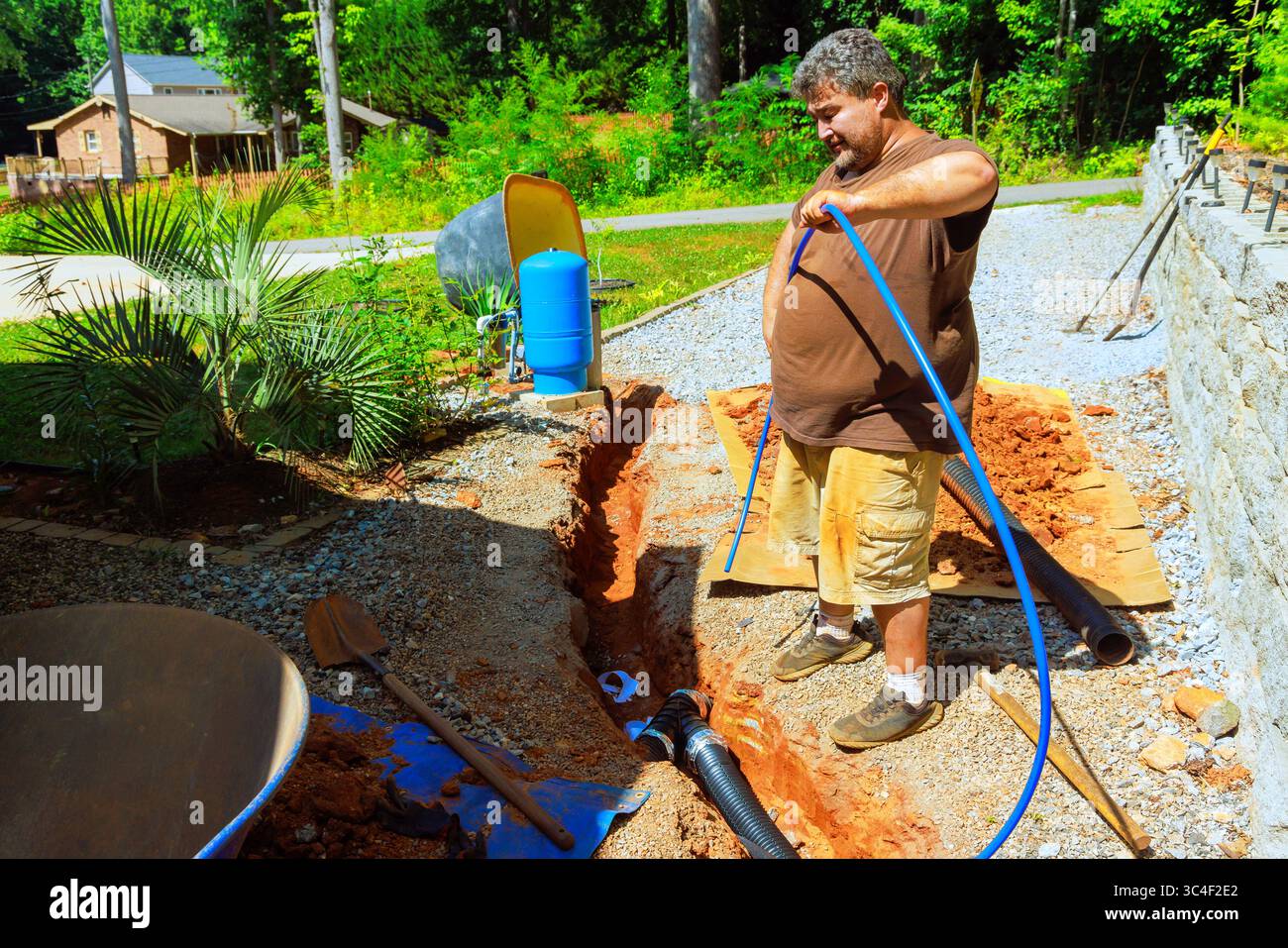 Individual is installing an water pump well system in yard while ...
