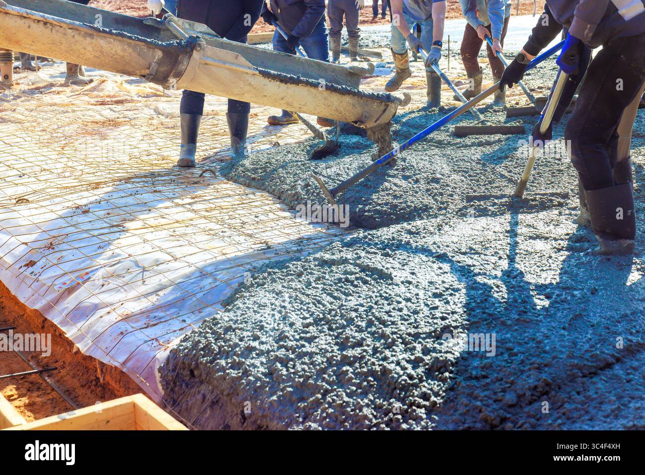 Laborers are pouring concrete at construction site, on laying to ...