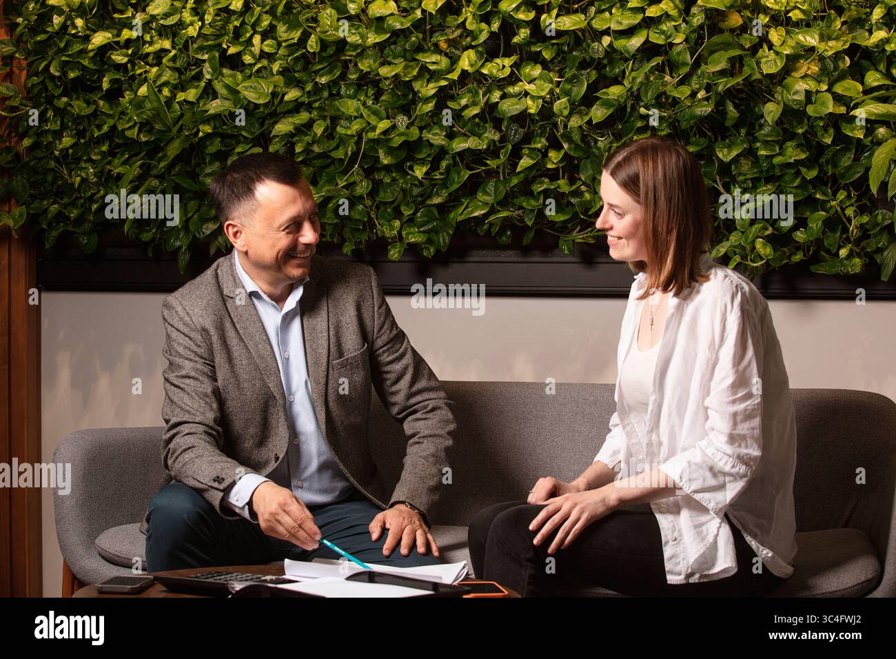 Two business partners laughing together while discussing documents in a ...