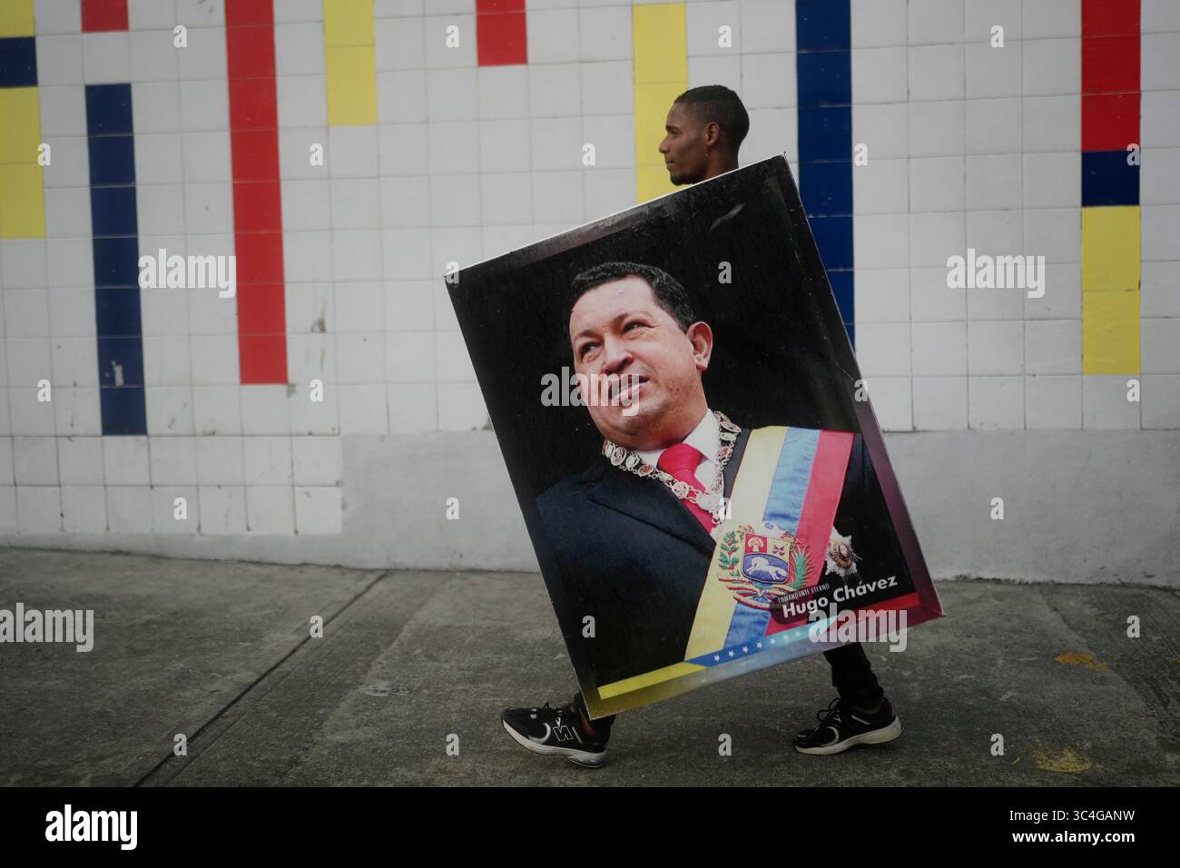A man carries a poster of late President Hugo Chavez to a rally marking ...