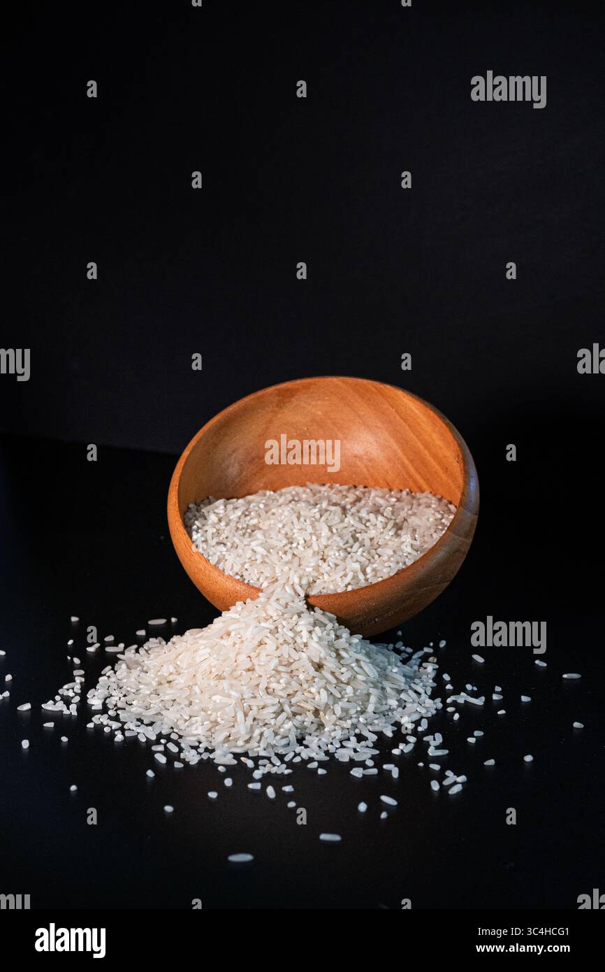 White rice in a wooden bowl set against a black background. Perfect for ...