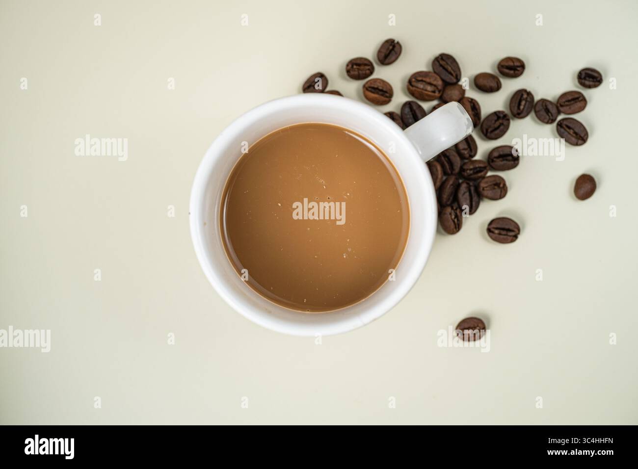 Flat lay of a white cup of coffee with coffee beans on a light ...