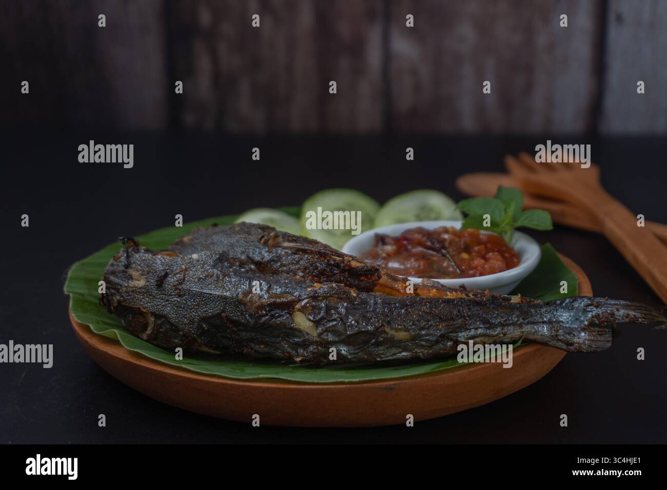 Fried catfish (pecel lele) with spicy sambal and basil leaves, served ...