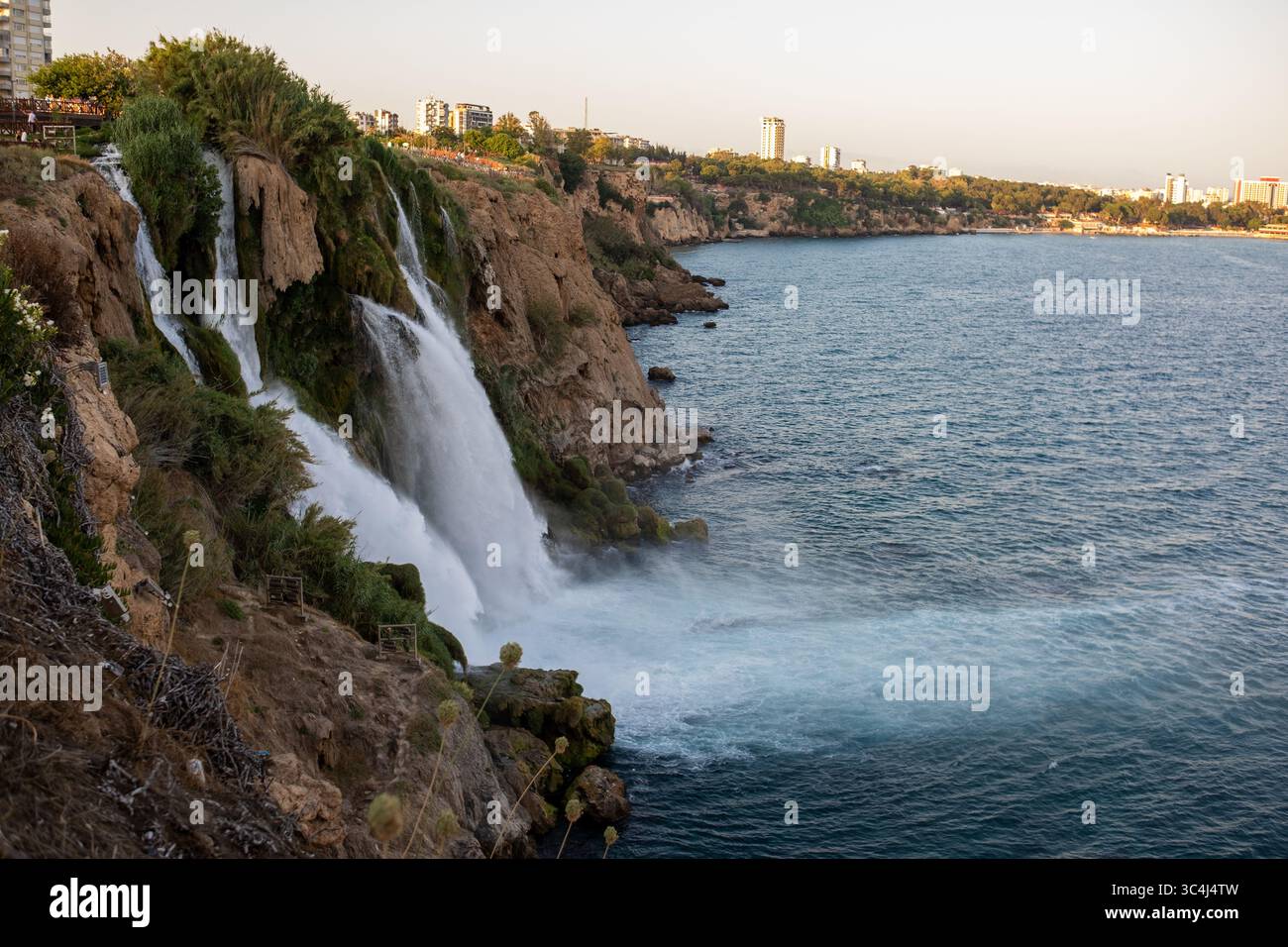 Waterfall Cascading Into the Sea at Sunset With City Skyline in the ...