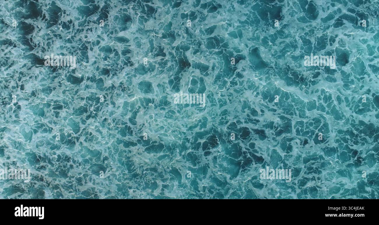 Drone view of turquoise ocean water surface with foam and waves ...