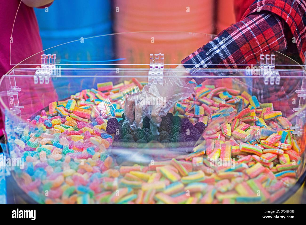 picking up jelly candies from a transparent container in the candy ...