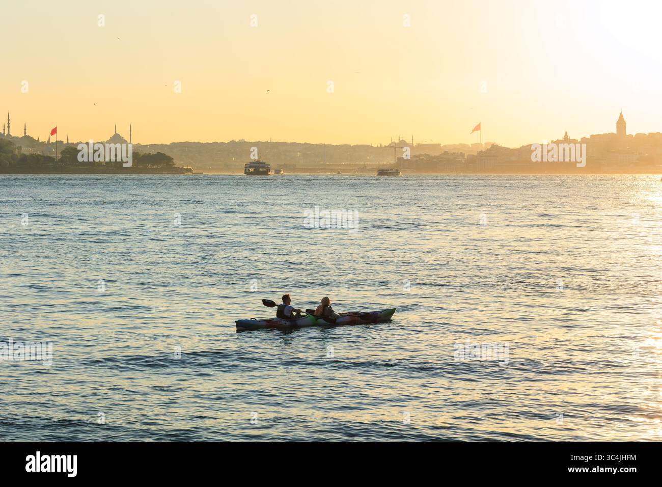 people in a single canoe is rowing on the bosphorus with a historical ...