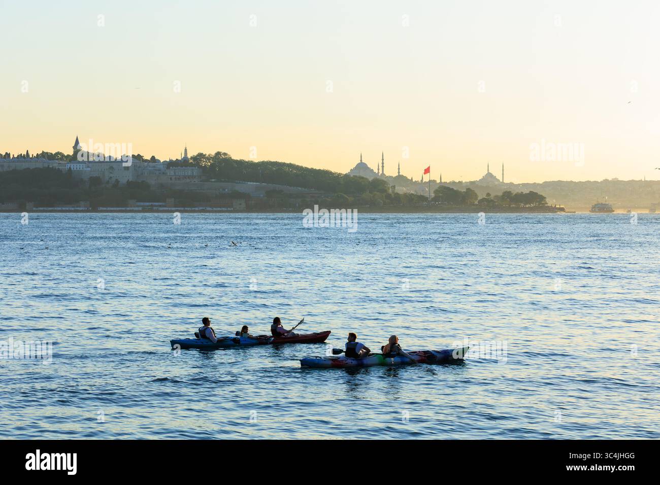 people in two canoes is rowing on the bosphorus with a historical ...