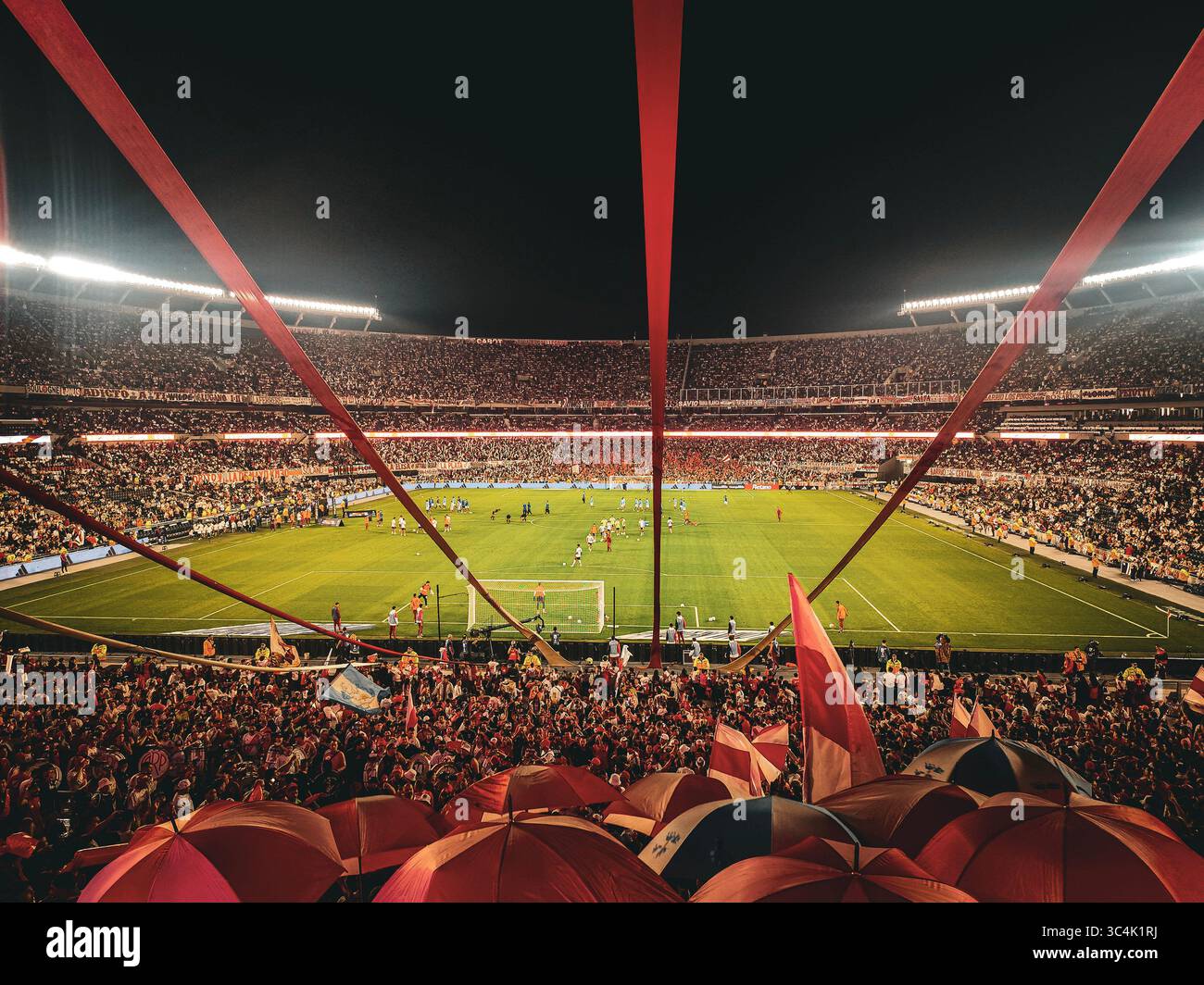 Fans of River Plate cheer behind red flags and umbrellas at Estadio ...