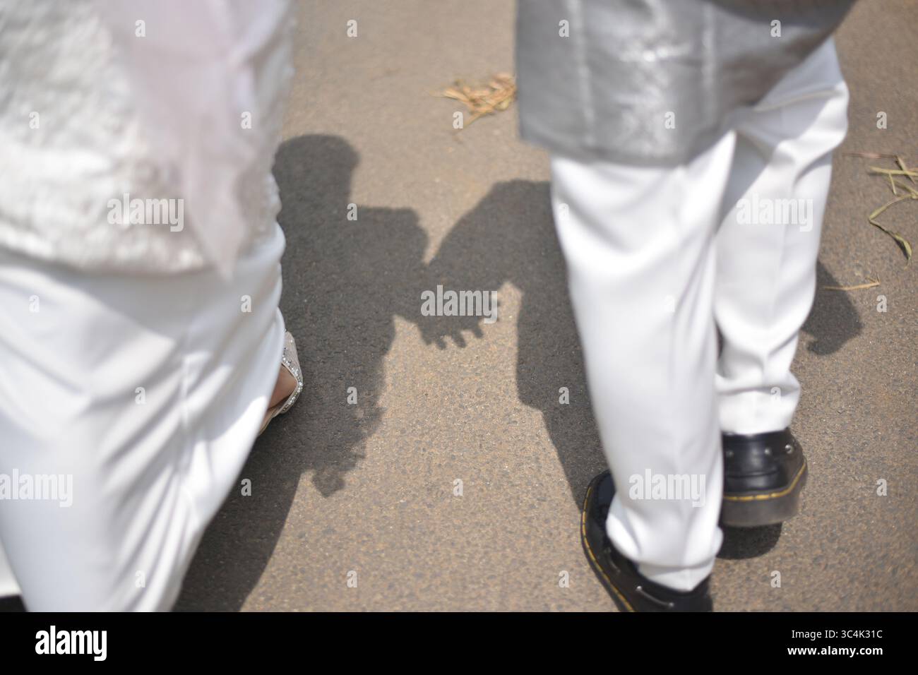 A close-up image showing two people holding hands in sunlight, casting ...