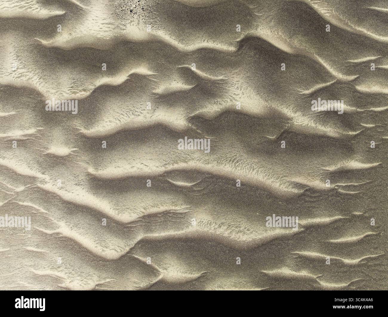 Aerial view of wind-sculpted sand dunes create mesmerizing patterns ...