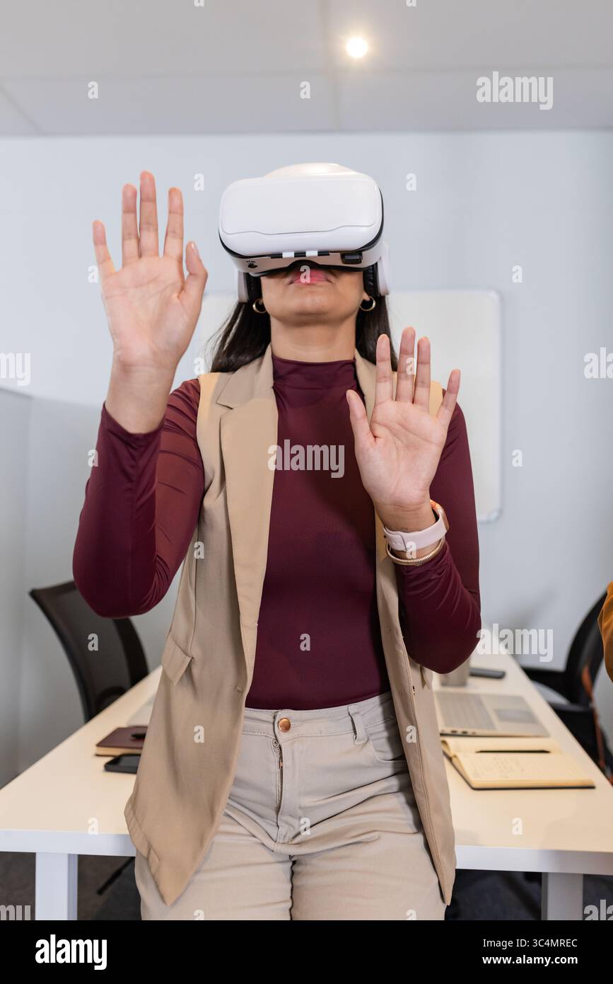 Woman wearing VR headset interacting with virtual interface at meeting ...