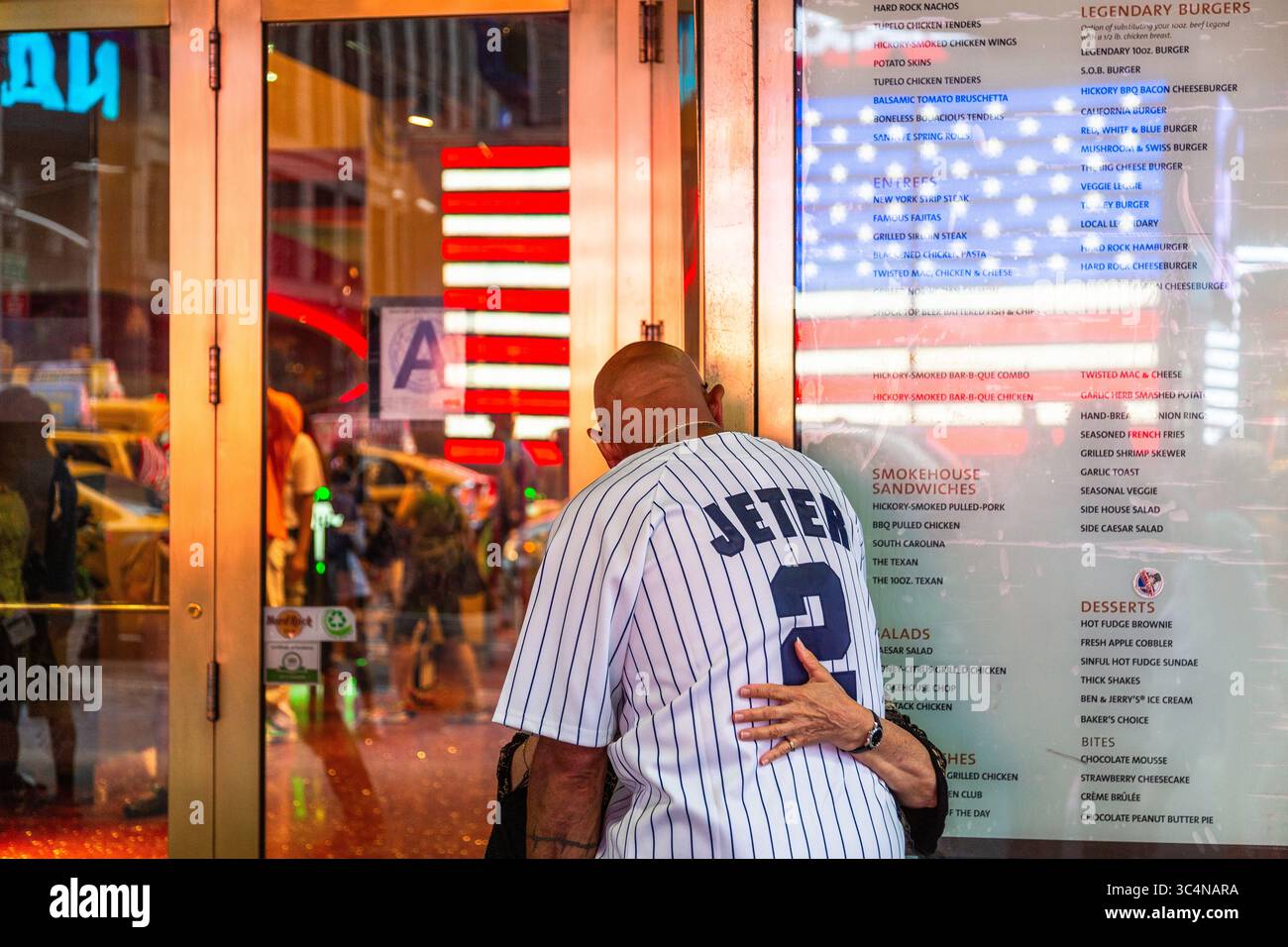Man held by the waist by someone else, in front of a window reflecting ...