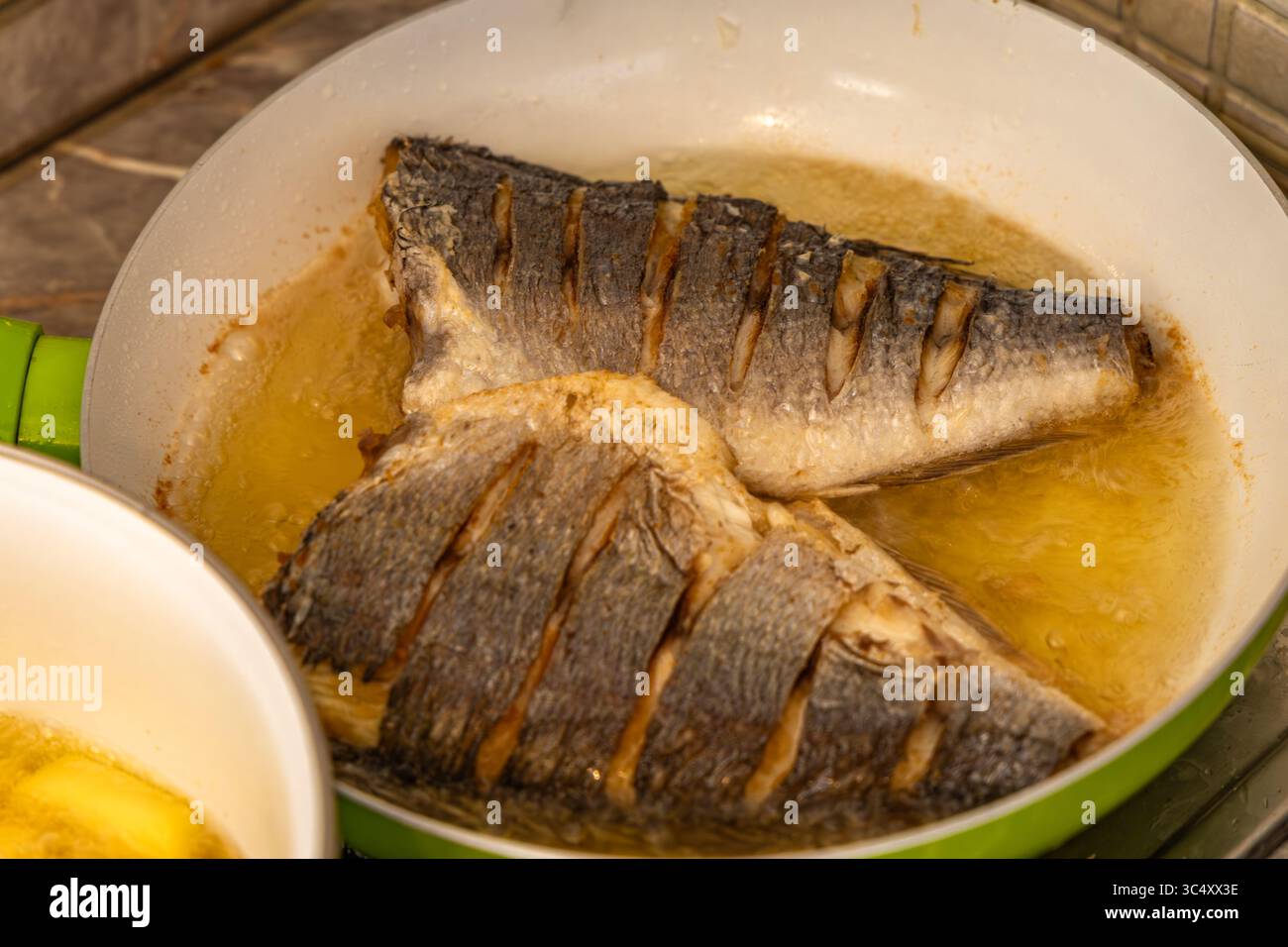 Two pieces of fresh fish fried in a pan, healthy food, fish seasoned ...