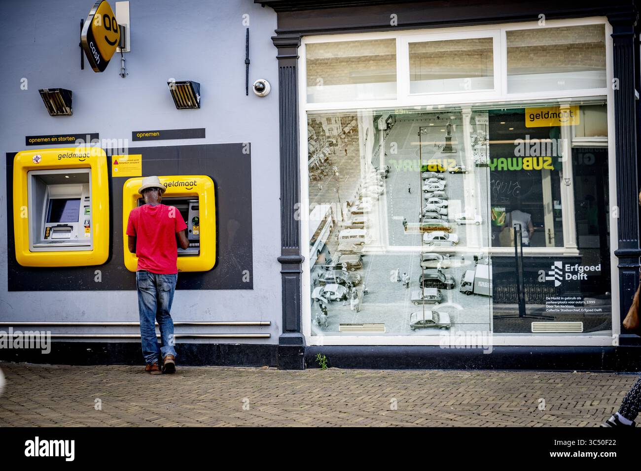 DELFT - A money size ATM a customer is withdrawing money from a machine ...