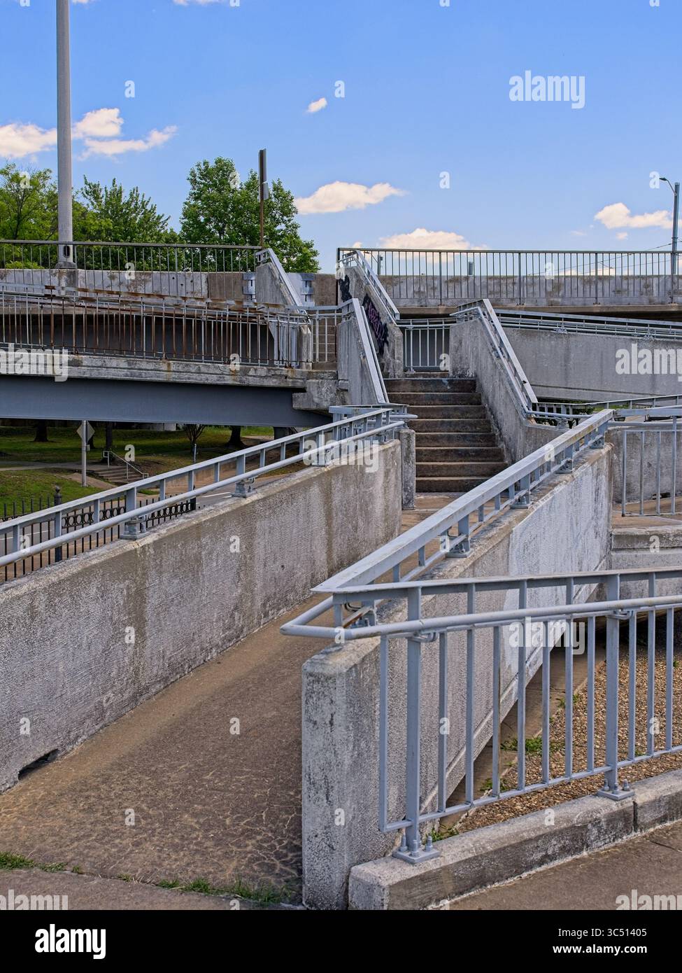 Concrete access ramp and stairs climb upward to pedestrian bridge Stock ...