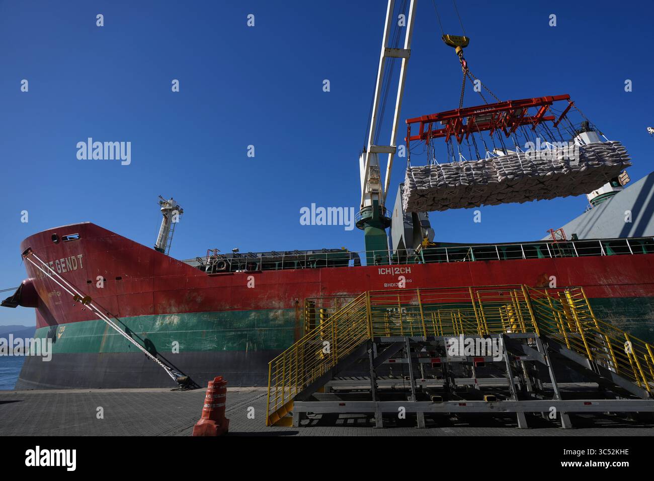 Bulk bags of sugar are lifted by a crane to be loaded on a container ...