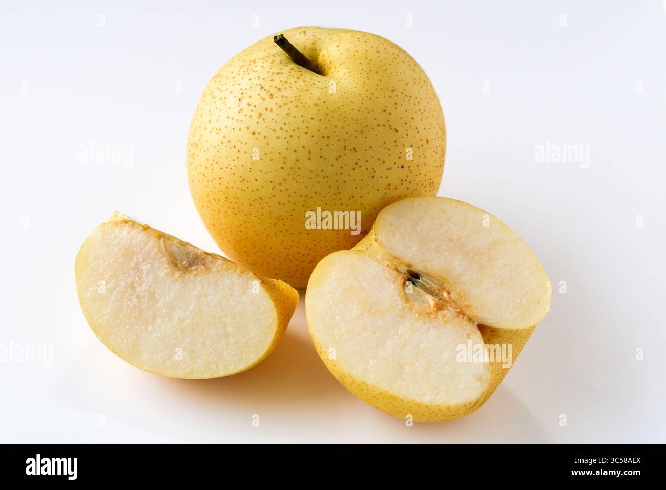 A fresh Asian pear, with one whole fruit, slice and another cut in half ...