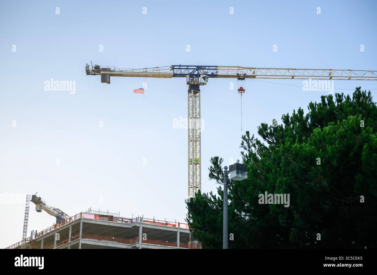 Construction cranes over a commercial building. American flag on a ...