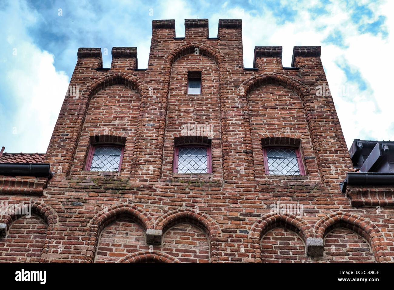 A low-angle architectural detail of the red brick facade of a medieval ...