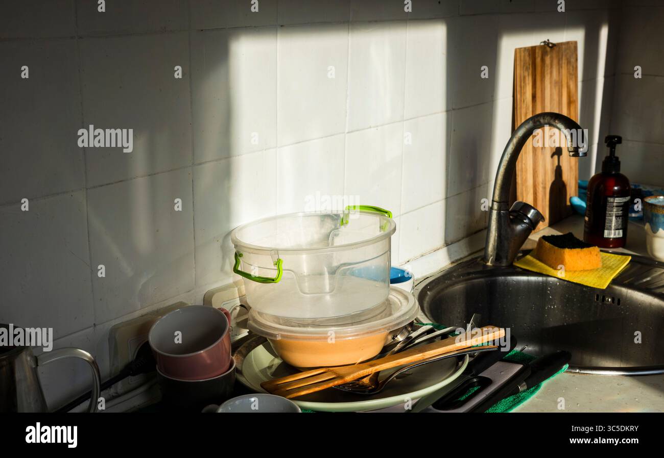 Dirty dishes, cutlery, cups, and plastic containers cluttering a ...