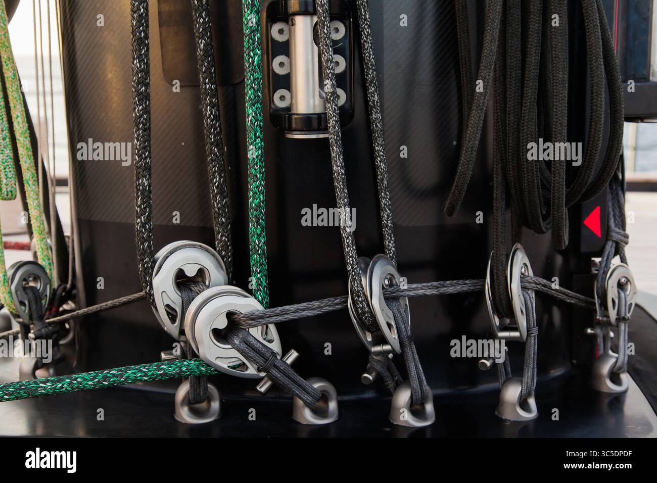 Part of the mast and hull of a sailing yacht, with multi-colored ropes ...