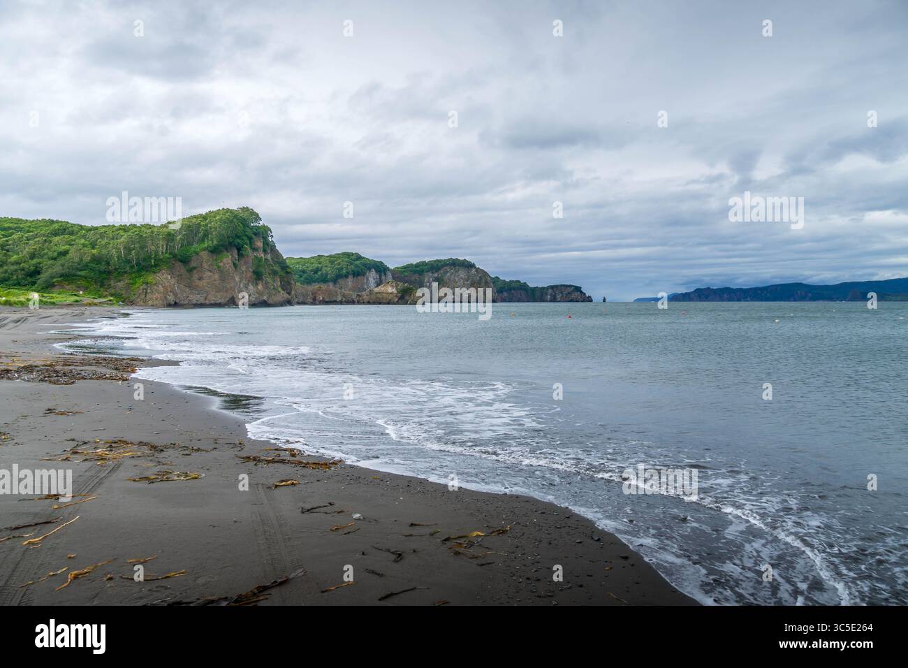 Scenic Kamchatka Peninsula coast under brooding sky, waves lapping ...