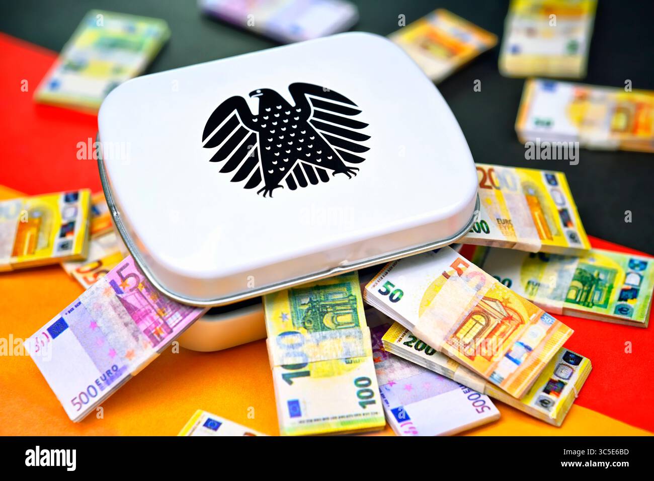 Box mit Bundesadler und Geldscheinen auf Deutschlandfahne ...